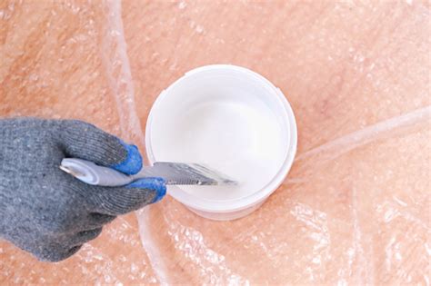 한 남자가 특수 플라스틱 교반기로 흰색 아크릴 페인트를 저어줍니다 문 페인팅 캔에 대한 스톡 사진 및 기타 이미지 캔