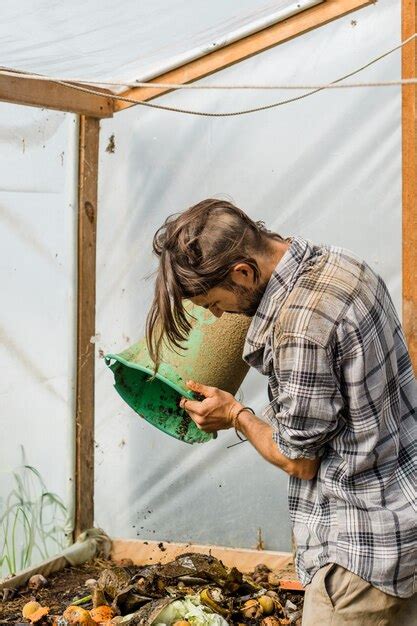 Premium Photo Caucasian Man With A Pot Of Compost In A Greenhouse