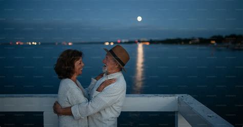 사랑에 빠진 행복한 노부부는 달빛을 받으며 바닷가 부두에서 야외에서 껴안고 서로를 바라보고 있다 사진 Unsplash의 달빛 이미지