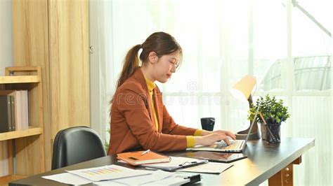 Smiling Young Business Working At A Home Office Desk With Laptop And