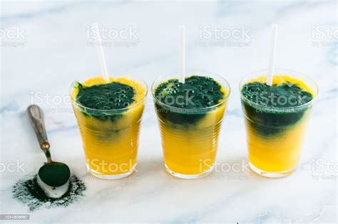 신선한 딸기와 안경에 두 색된 신선한 스무디 오렌지 바나나 주스 Spirulina 파우더입니다 아침 식사를 해독 건강 한 식습관