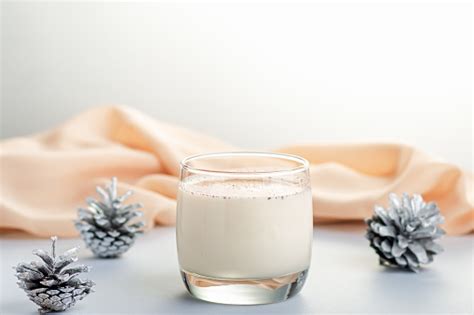 계란 알코올 강판 육두구와 계피 클로즈업 복사 공간을 가진 전통적인 크리스마스 칵테일 Eggnog 베이지 색 장식 불타는 등불과