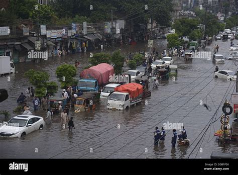 Pakistani Commuters Wade Through A Flooded Road After Heavy Monsoon
