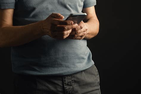 한 남자가 모빌 전화로 문자를 보내는 장면이 잘렸습니다 어두운 배경의 실내 환경 읽기에 대한 스톡 사진 및 기타 이미지 읽기