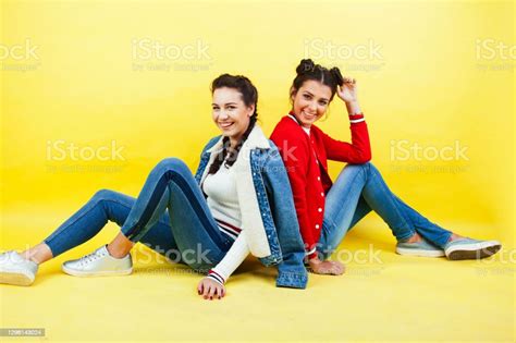 ライフスタイルの人々の概念黄色の背景に笑顔で楽しい幸せな2人のかなり若い学校の十代の女の子 1人のストックフォトや画像を多数ご用意 1