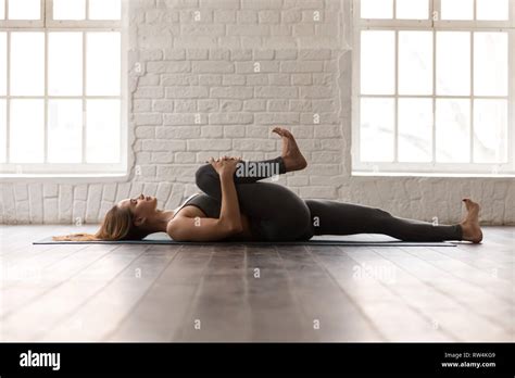 Woman Practicing Yoga Lying In Knees To Chest Pose Apanasana Stock