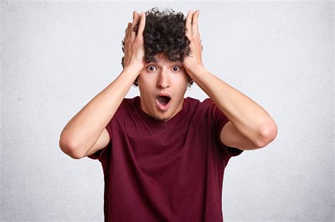 충격의 초상화는 작은 수염과 검은 곱슬 머리와 두 손으로 그의 머리를만 지는 감동 잘생긴 남자 얼굴 표정을 걱정 입과 눈을 크게