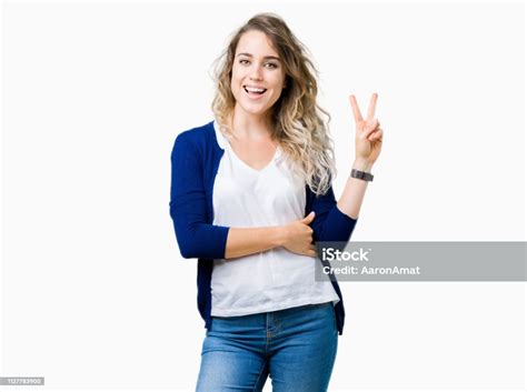 아름 다운 젊은 금발 여자 승리 기호를 수행 하는 카메라에 행복 한 얼굴로 웃 고 고립 된 배경 위에 2 번 한 명의 여자만에