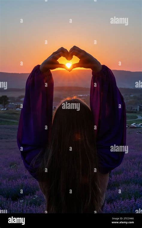 Woman Creates Form A Heart Shape With Hands At Sunset Conveying Serene