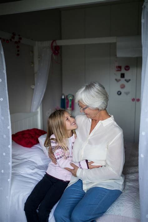 Smiling Grandmother And Granddaughter Embracing Each Other On Bed Stock