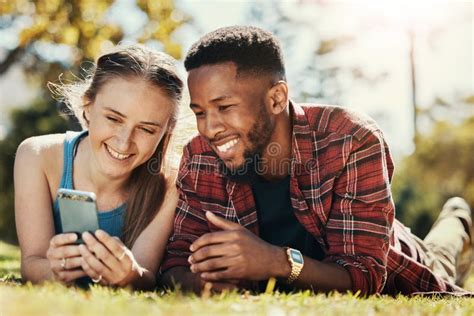 Interracial Couple And Phone Social Media In Park To Relax Bond And