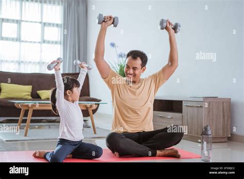 Happy Father And Daughter Exercising Doing Dumbbell Lifting Together