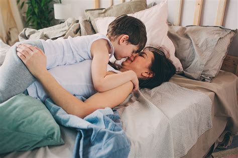 행복 한 어머니는 집에서 침대에 앉아 아침에 그녀의 유아 아들을 안 아 캐주얼 라이프 스타일 가족 생활 가정 생활에 대한 스톡