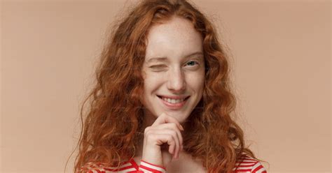 진취적이고 열정적으로 보이는 복숭아 배경에 고립된 잘생긴 빨간 머리 십대 소녀의 스튜디오 헤드샷 모험에 초대하거나 좋은 혜택을 추천하는 것처럼 친근하게 윙크합니다 사진