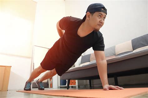 새로운 정상적인 라이프 스타일 실내 홈 운동 한 쪽 팔 푸시 업 판자 위치에 건강을 유지하기 위해 집에서 운동을하는 아시아 남성