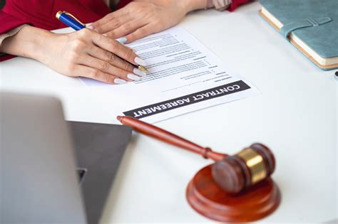 계약서에 서명하는 아시아 여성 변호사 또는 법률 고문 법률 사무소의 책상 위에서 작동하는 계약 문서가 귀하를 안내하기 위해