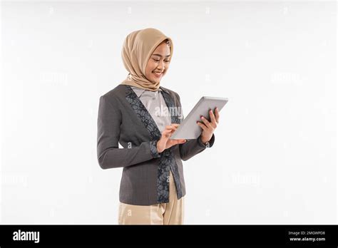 A Woman With Hijab And Gray Blazzer Standing Looking At The Tablet