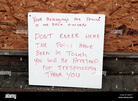 sign outside empty property inhabited by squatters where the owners