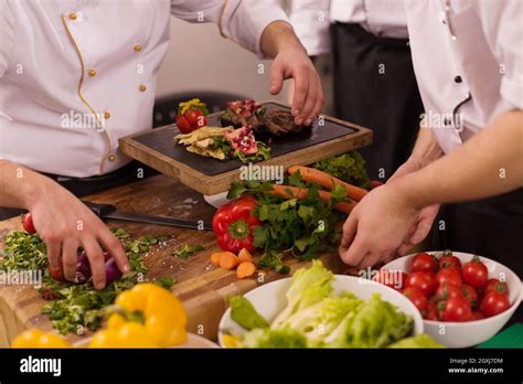 Professional Team Cooks And Chefs Preparing Meal At Busy Hotel Or