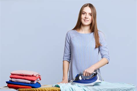 하드 작업 여성 바쁜 집 작업의 절연된 샷 세탁에 푸른 배경 위에 절연 전기 철 옷 아이언 여자 착용 세련 된 블라우스 다림