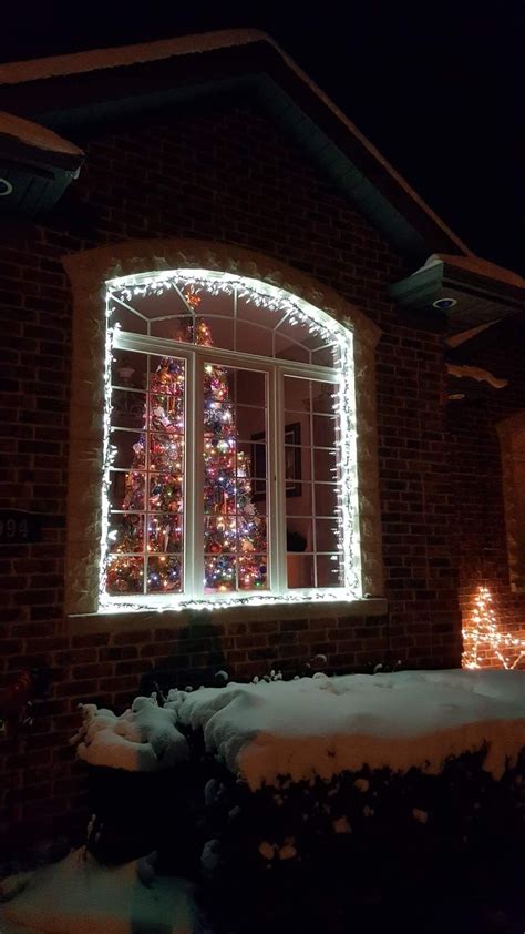A Lighted Christmas Tree In The Window Of A House