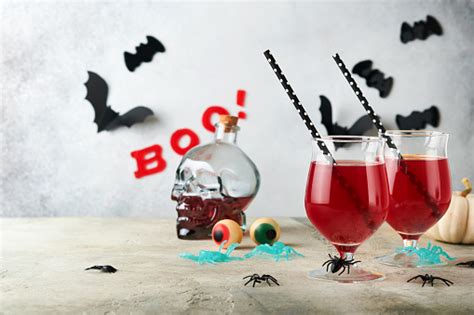 할로윈 피 묻은 칵테일 할로윈을 위한 두 개의 피 묻은 칵테일 유리 잔과 밝은 배경에 병 형태의 두개골 사탕 눈 박쥐 거미 및 호박과 함께 할로윈 파티를위한 장식 개념 0