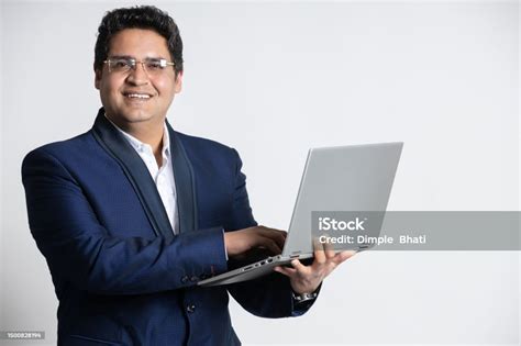 양복과 안경을 쓰고 웃고 있는 젊은 인도 사업가가 하얀 스튜디오 배경에 고립된 노트북으로 작업하고 있다 컴퓨터를 사용하는 아시아 기업 남성 금융에 대한 스톡 사진 및 기타
