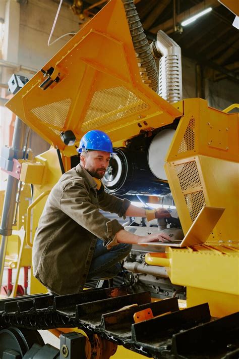 Premium Photo Technician Using Laptop While Fixing Parts Of Bulldozer