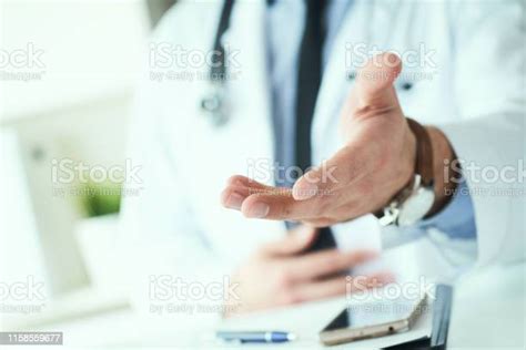 환영 제스처를 만드는 남성 의사 정중 하 게 의료 사무실에 앉아 환자를 초대 피사계 심도가 있는 사진 건강 진단에 대한 스톡 사진 및 기타 이미지 Istock