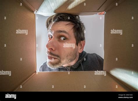 Young Curious And Suspicious Man Is Looking Inside Cardboard Box Stock