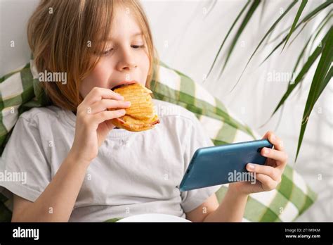 Relaxing In Bed A Year Old Boy With Flowing Hair Enjoys His Time Online And Gaming On His