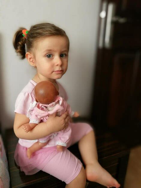 Premium Photo Portrait Of Cute Girl With Doll Sitting At Home