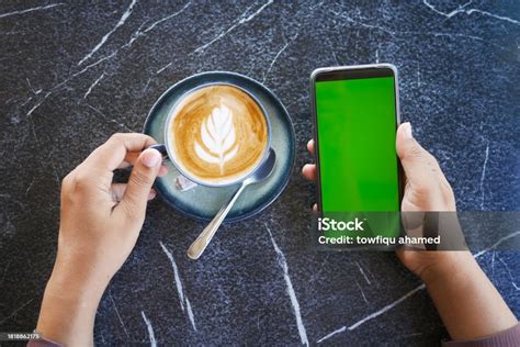 그린 스크린이 있는 스마트폰과 테이블 위의 커피 한 잔을 들고 있는 손 0명에 대한 스톡 사진 및 기타 이미지 0명 Brand Name Smart Phone 라떼