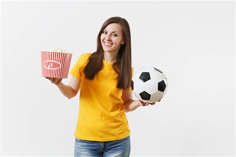 흰색 배경에 고립 유럽 젊은 여자 축구 팬 또는 플레이어 노란색 유니폼 축구공 팝콘의 물통을 들고 웃 고 스포츠 놀이 축구 응원
