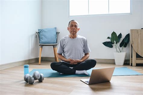 Premium Photo Asian Senior Man Meditating On Mat Learning Yoga Online