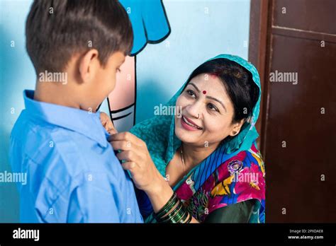 Young Happy Indian Mother Wearing Sari Getting Her Son Ready For School