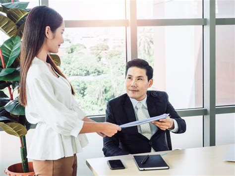Asian Businessman Boss Working With Young Woman Secretary On Desk In