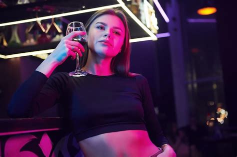 Mujer Joven De Pie En El Club Nocturno Con Bebida En La Mano Foto Premium