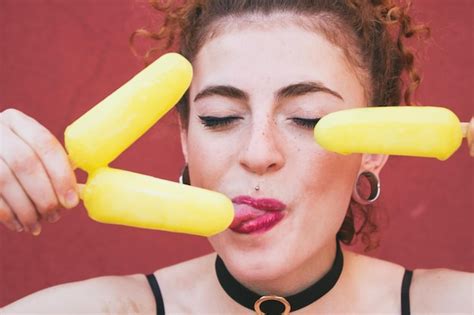Premium Photo Close Up Of Young Woman Eating Yellow Popsicles