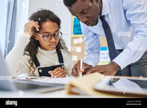 Portrait Of Male Teacher Helping Young African American Schoolgirl