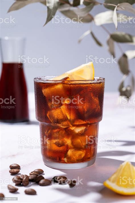 明るい大理石の背景に氷とレモンとグラスにコーヒー豆とボトルの接写夏のクラフト爽やかな自家製ドリンクをコンセプトに かんきつ類のストック
