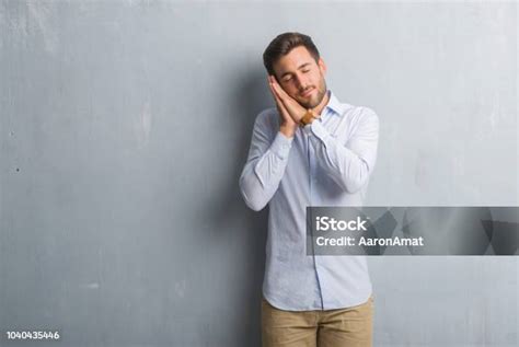 자 고 피곤 꿈 닫힌된 눈으로 웃 고 하는 동안 함께 손 포즈 우아한 셔츠를 입고 회색 그런 지 벽에 잘생긴 젊은 비즈니스 사람