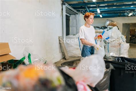 라텍스 장갑을 끼고 현대적인 개인 폐기물 재활용 공장에서 추가 처리를 위해 다양한 폐기물을 분류하는 잠겨 있는 젊은 여성 노동자
