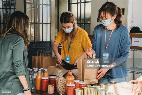 푸드 뱅크에서 옷 음식 및 음료로 상자를 준비하는 자원봉사자 그룹이 있습니다 30 34세에 대한 스톡 사진 및 기타 이미지