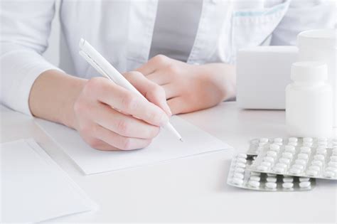 의사가 환자 치료를 위한 처방전을 작성입니다 사무실에서 의사를 방문 하십시오 의료 및 약국 개념입니다 테이블에의 다른 의약품