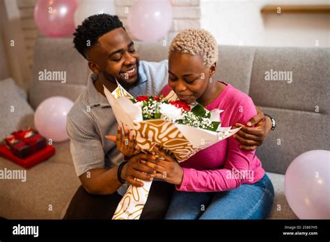 Happy Loving Couple Celebrating Woman S Birthday At Home Boyfriend Is Giving Bouquet Of Flowers