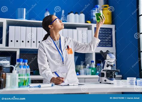 Young African American Woman Scientist Measuring Liquid At Laboratory