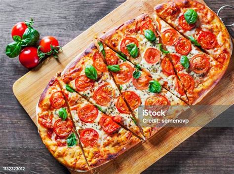 모 짜 렐 라 치즈 토마토 후추 향신료와 신선한 바 질이 있는 타원형 피자 이탈리아 피자입니다 피자 마르게리타 또는 마가리타에