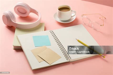 분홍색 탁자 위에 놓인 몇 가지 필수 작업 품목 사진 텅 빈 메모장 모닝 커피 한 잔 안경 및 분홍색 헤드폰 광고 그림 사본 공간을 위한 사무실 작풍 고용과 노동에 대한