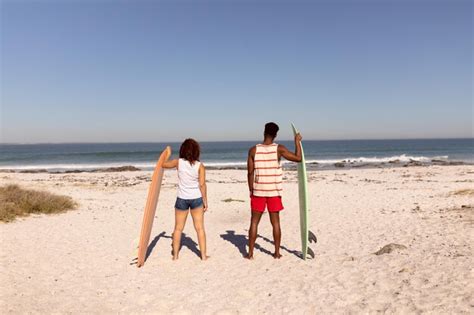 Couple Standing With Surfboard On Beach In The Sunshine Premium Ai